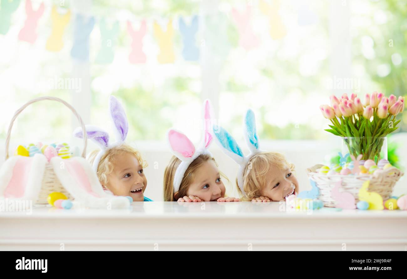 Kids dyeing Easter eggs. Children in bunny ears dye colorful egg for ...