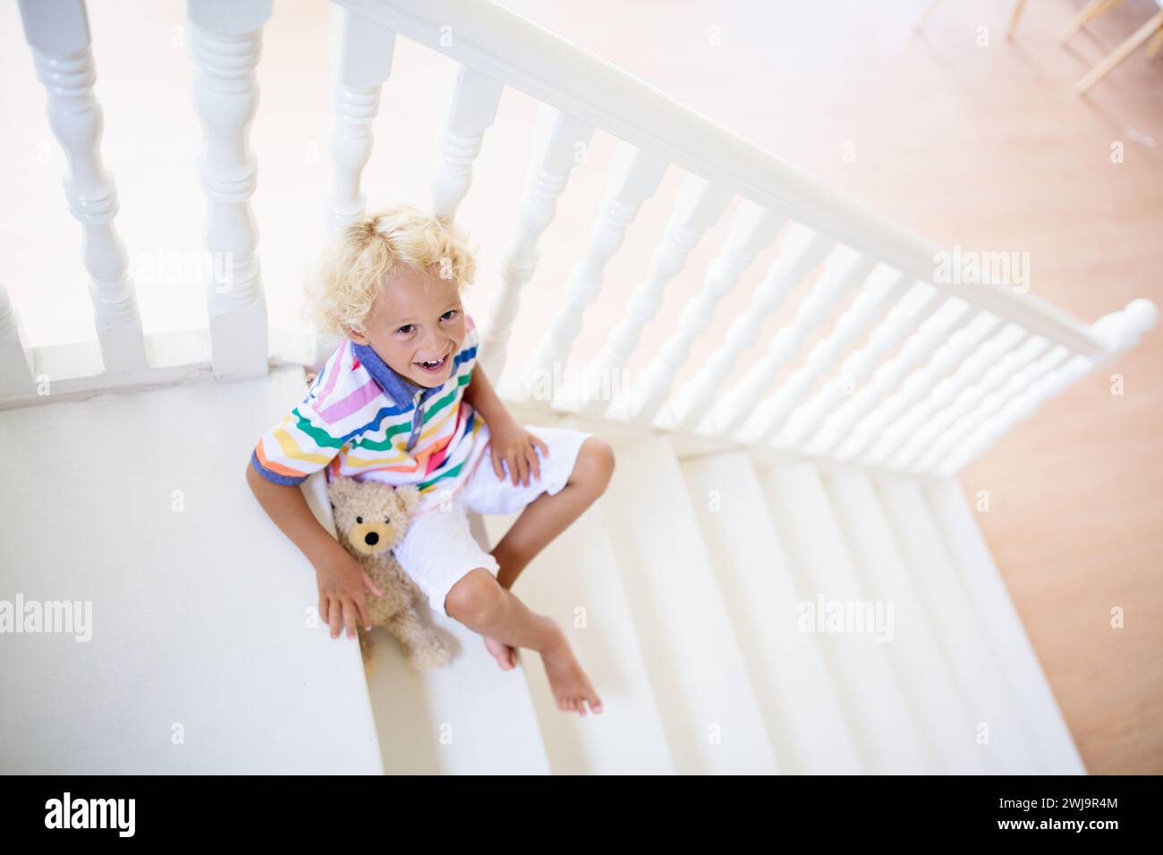 Kid walking stairs in white house. Little boy playing in sunny ...