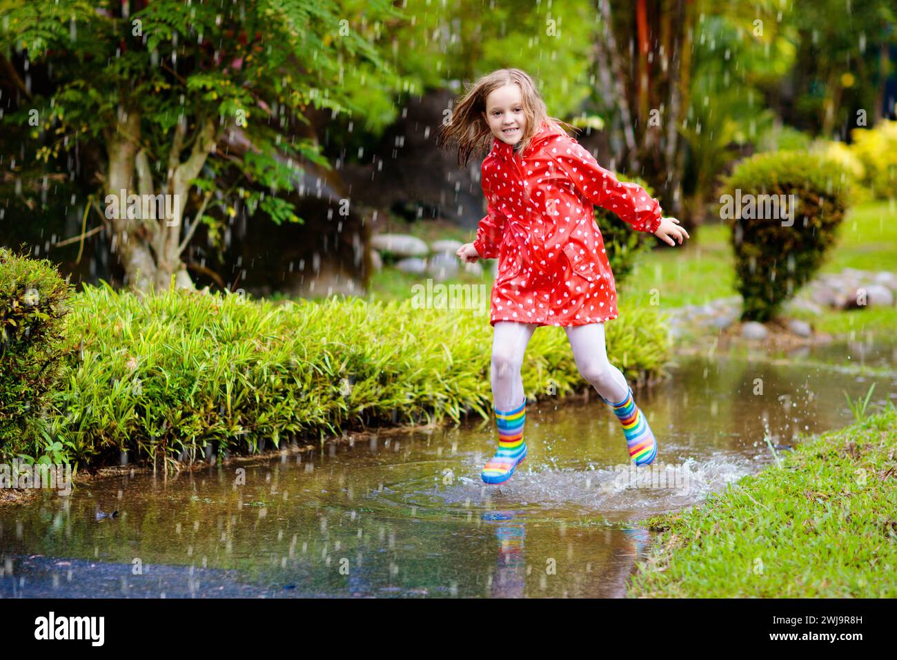 Child playing in puddle. Kids play and jump outdoor by autumn rain ...