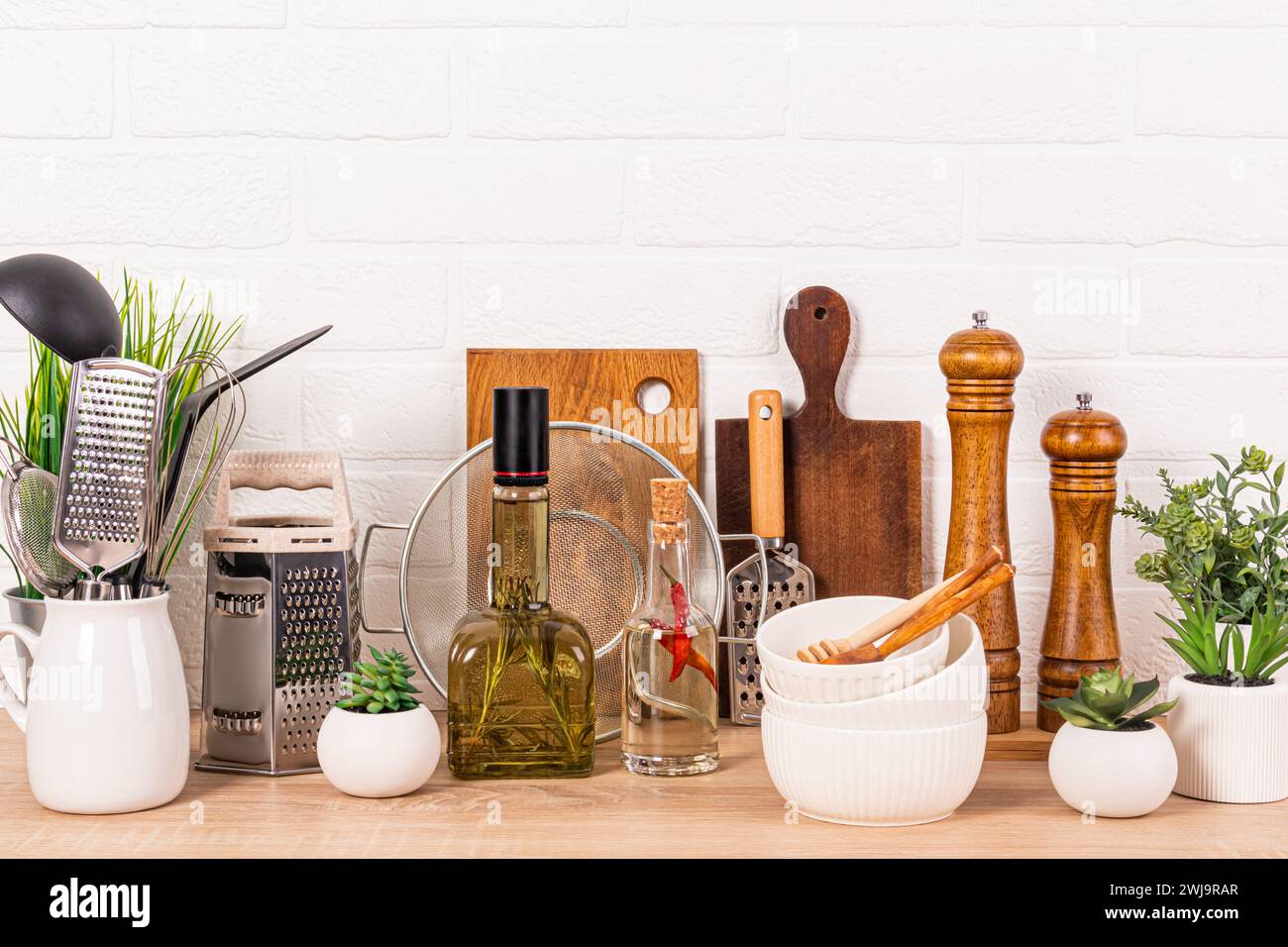 Lots of different kitchen utensils, oil bottles, spice mill and potted ...