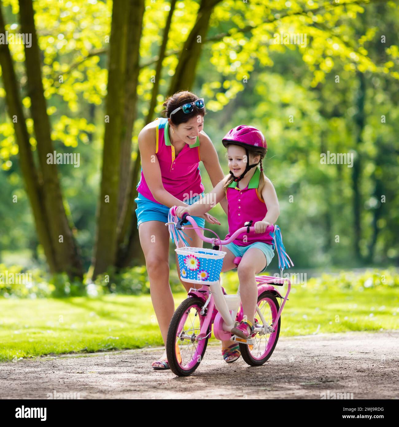 Child riding bike. Kid on bicycle in sunny park. Mother teaching little ...