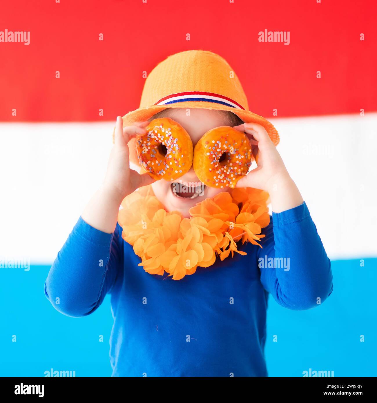Little Dutch boy girl wearing country symbols eating orange donuts ...