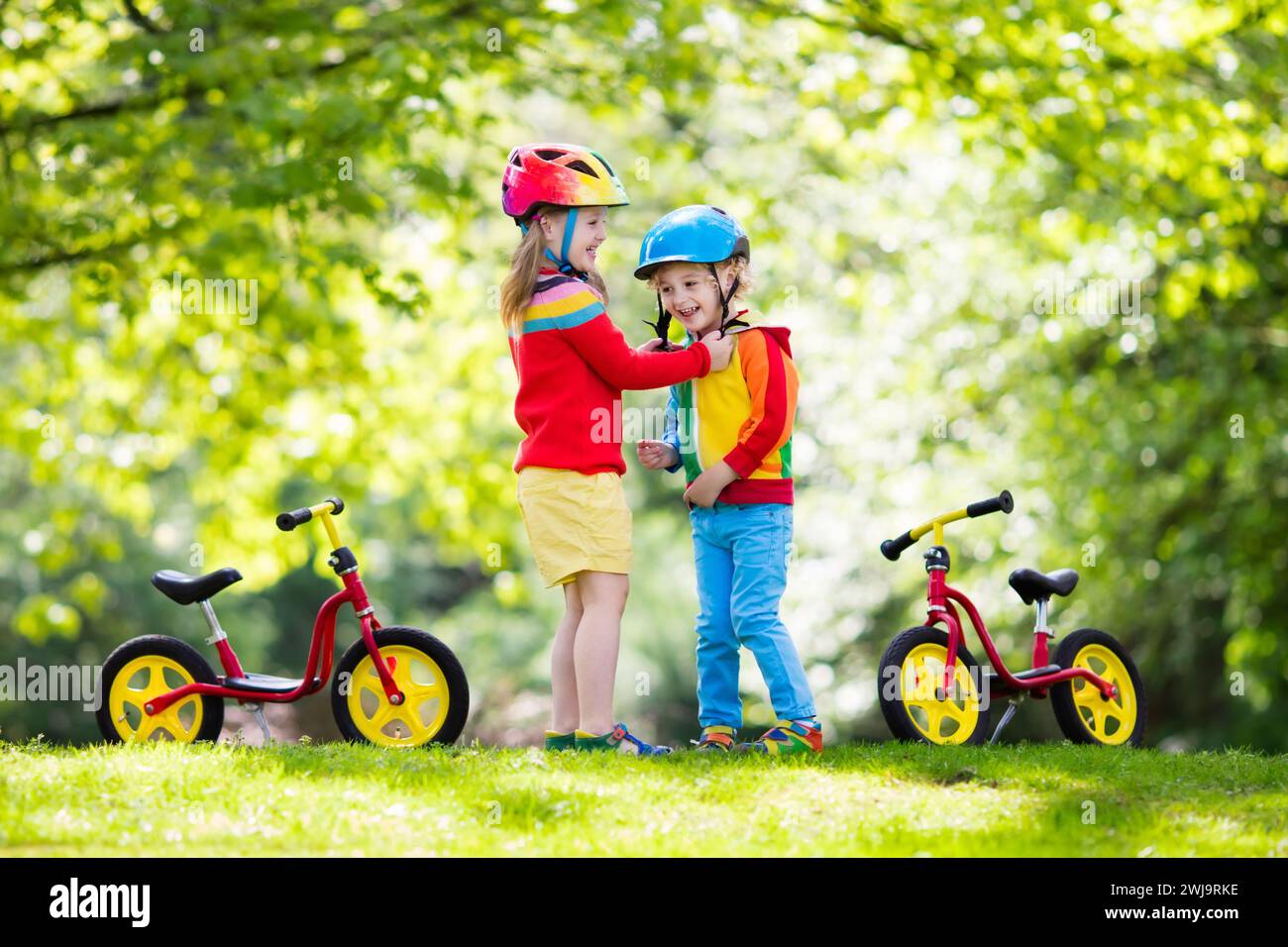 Children riding balance bike. Kids on bicycle in sunny park. Little ...