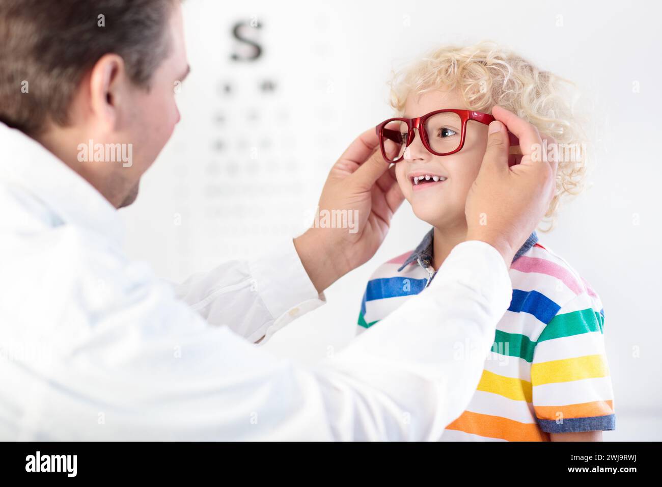 Child at eye sight test. Little kid selecting glasses at optician store ...