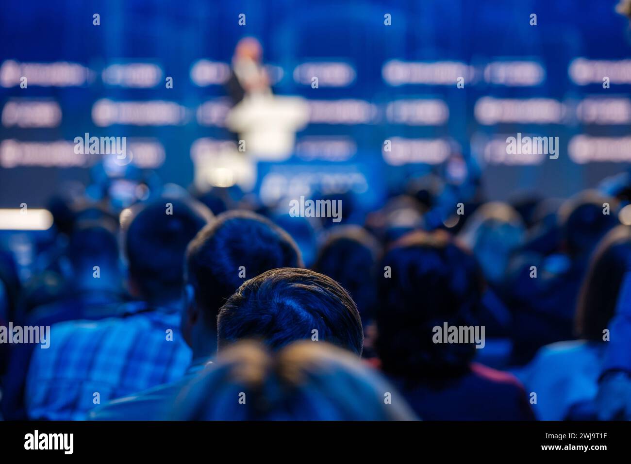 Blurred audience in focus watching a speaker at a conference with a ...