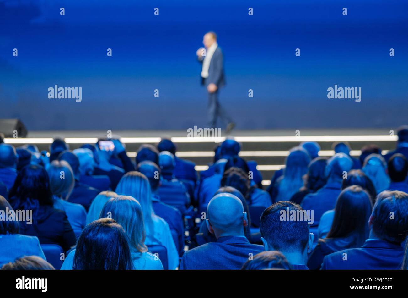 Audience listening to a speaker at a corporate event. Focus on engaged ...