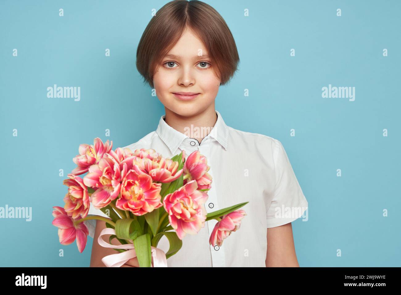Cheerful happy child with Tulips bouquet. Smiling boy on blue ...