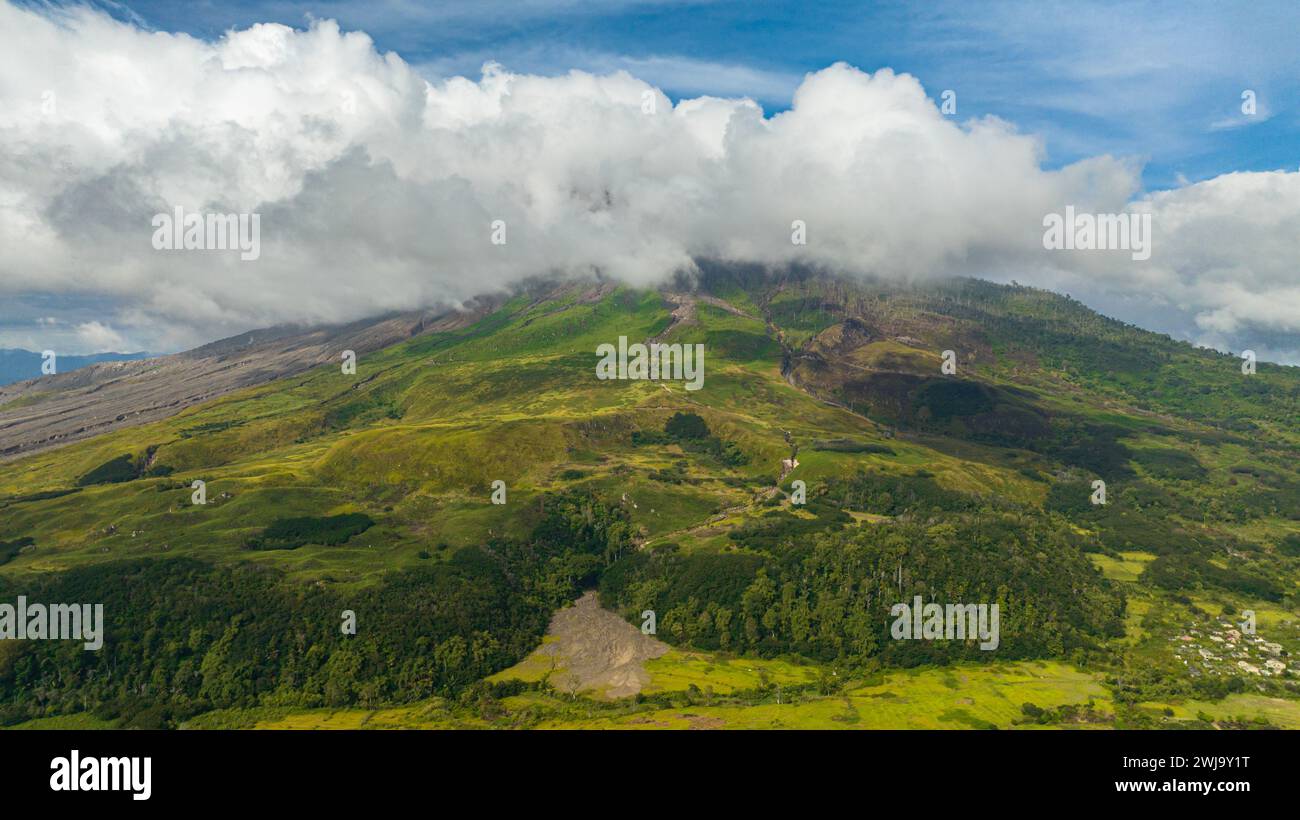 Aerial drone of Sinabung volcano with slopes covered with clouds after ...