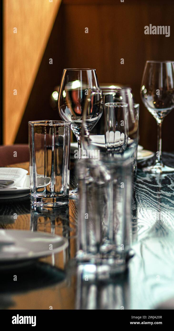Wooden table set with plates, glasses, silverware, and wine glasses ...