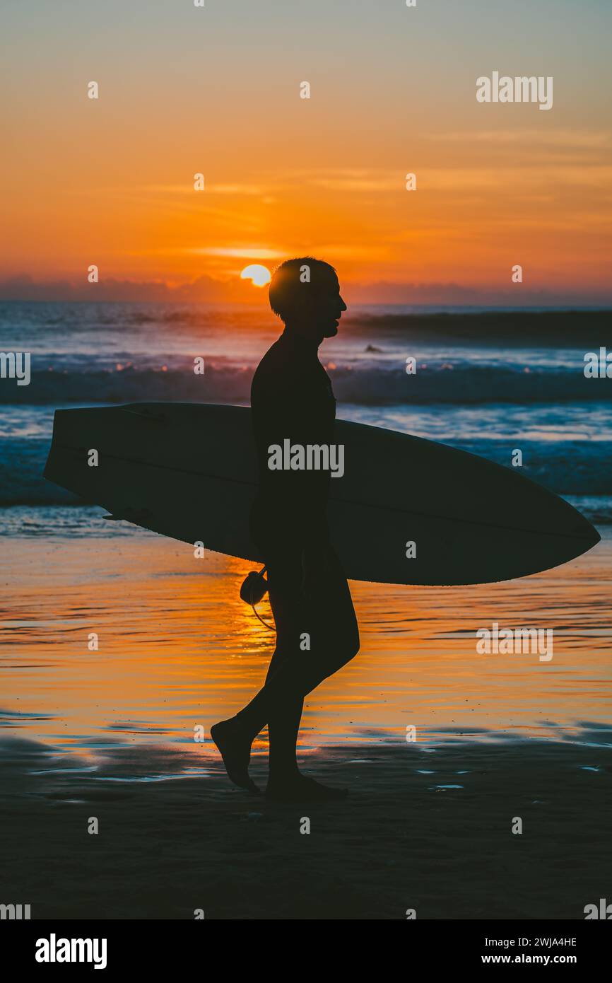 Side view of unrecognizable male surfer walking with surfboard on ...