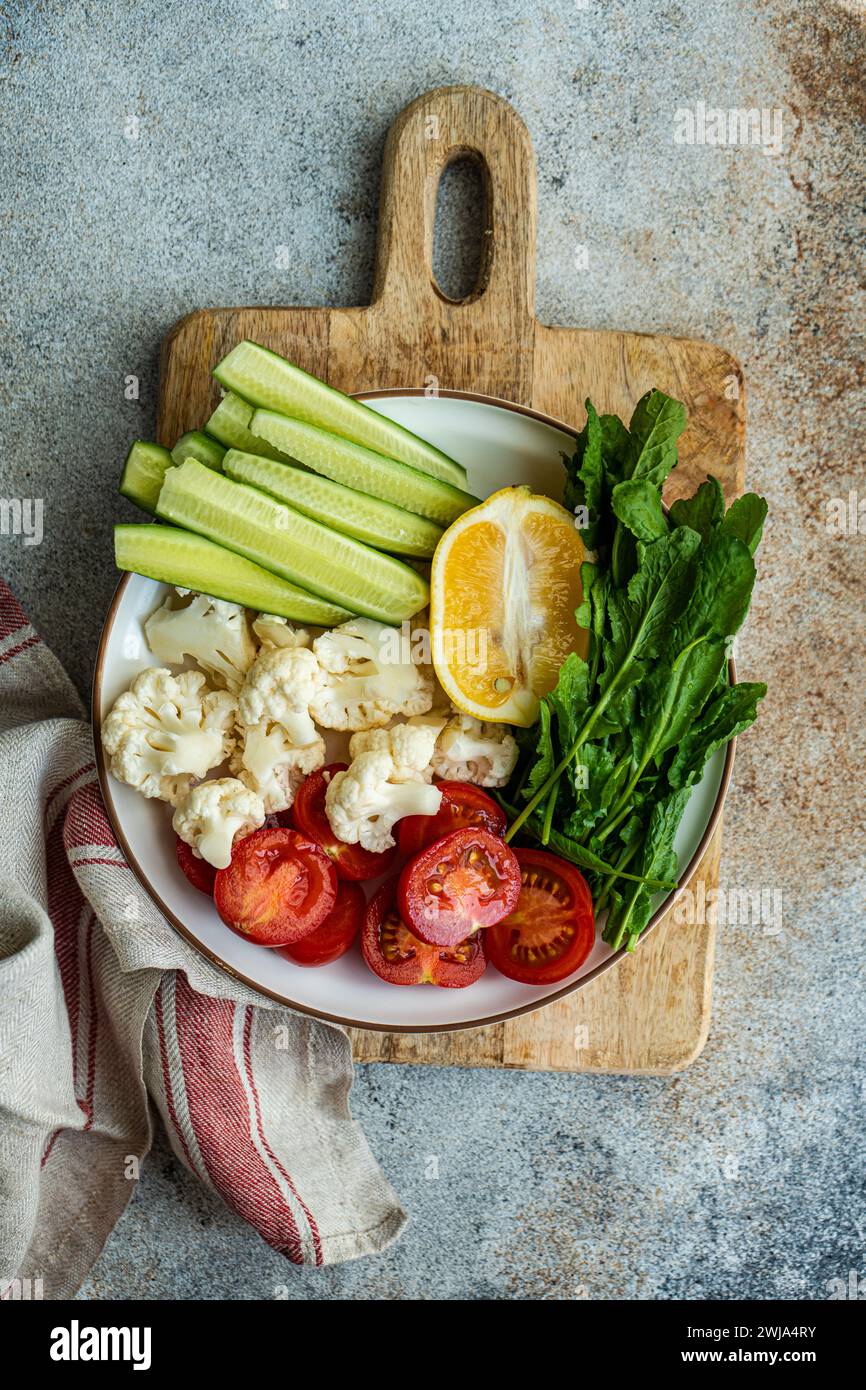 Top view of vibrant dish of raw vegetables with sliced cucumber, halved ...