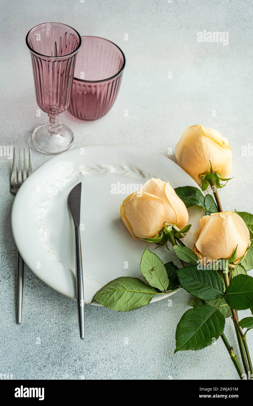 An intimate table setting featuring a white plate, silver cutlery, pink ...