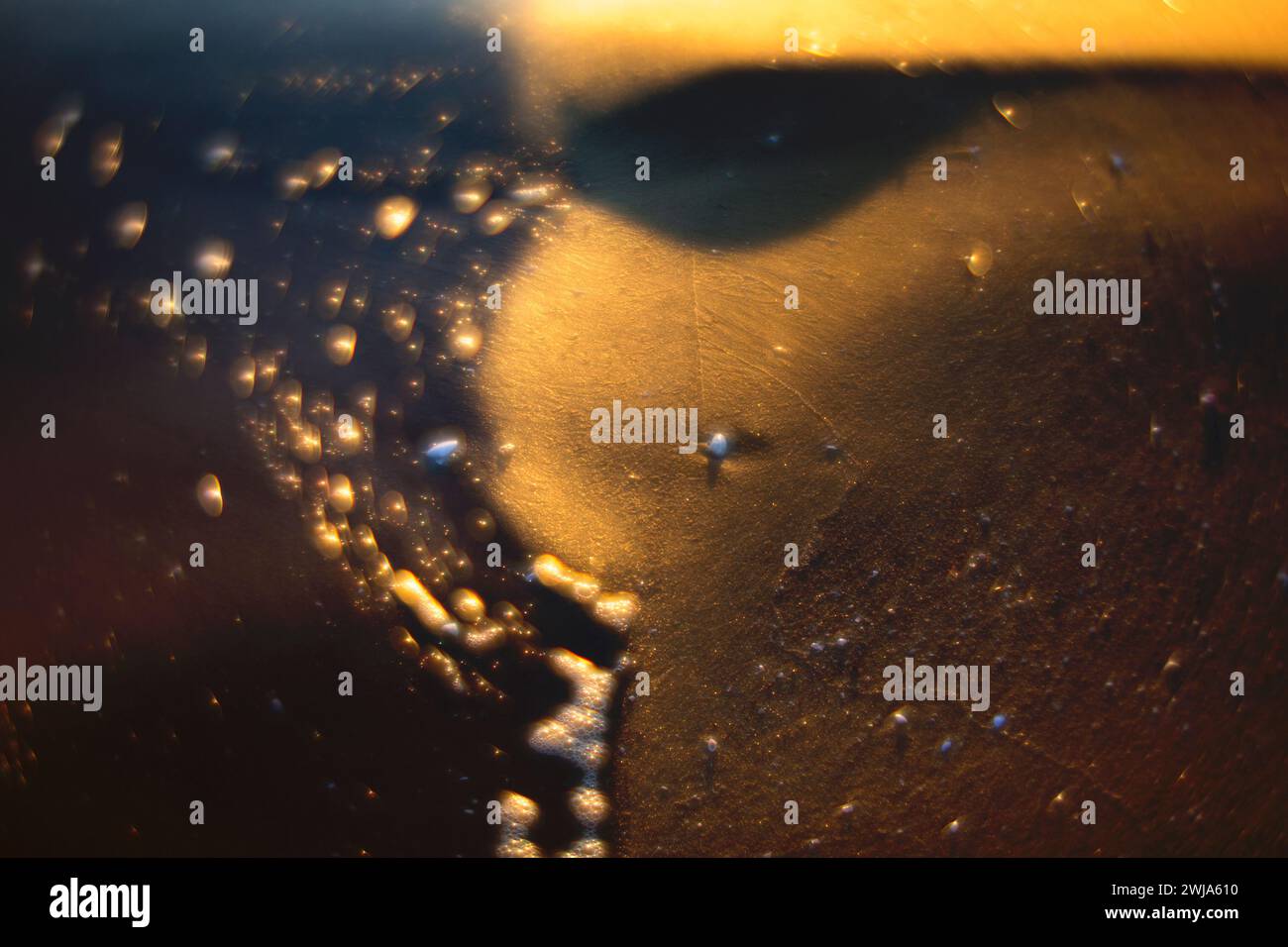 Close-up of golden droplets on a surface with a blurred shadow, evoking ...