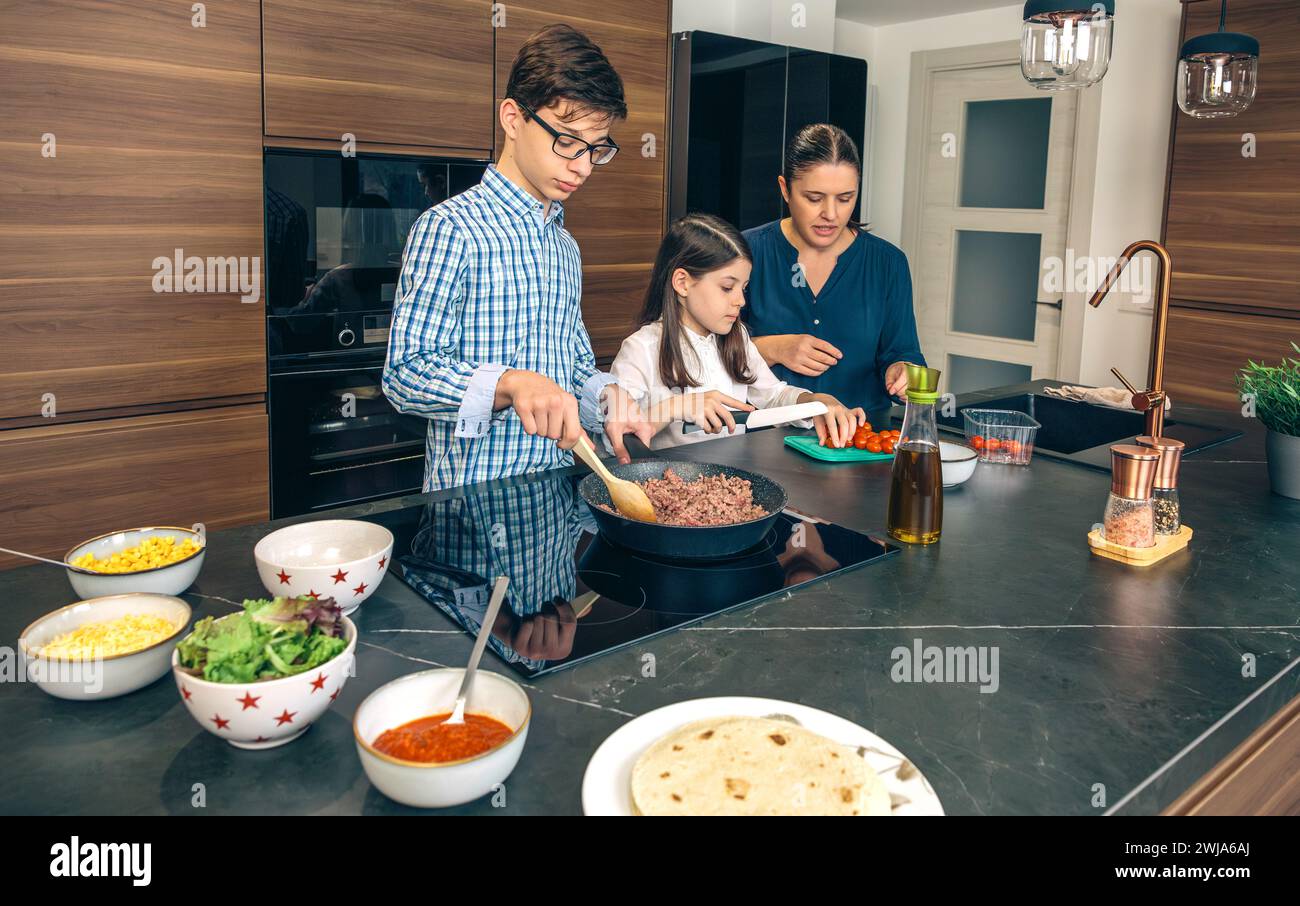A mother and her children prepare a taco dinner in the kitchen, with ...