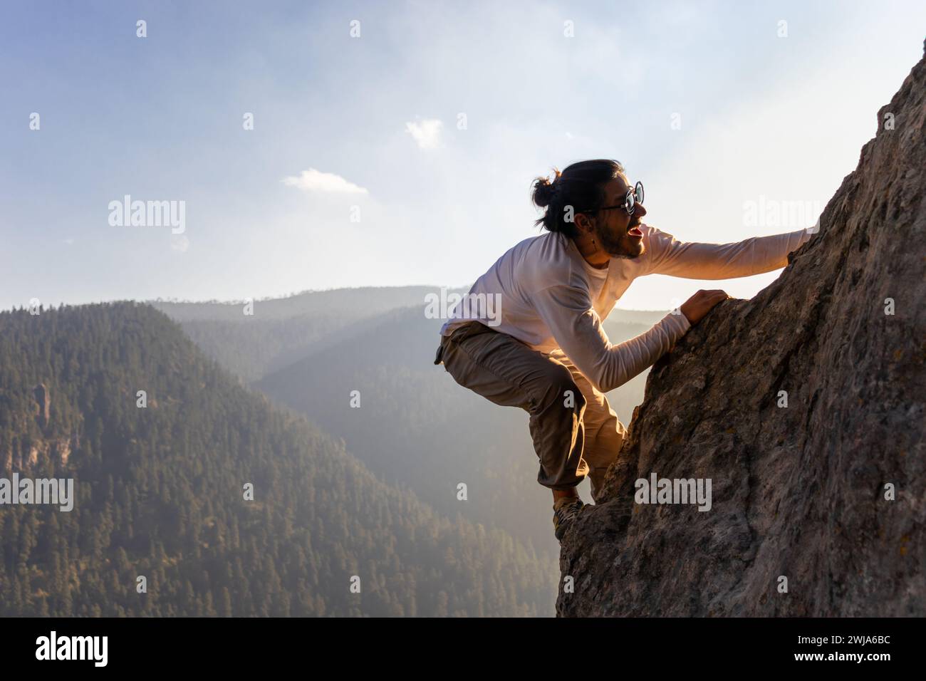 Full body of positive male in stylish clothes and sunglasses climbing ...