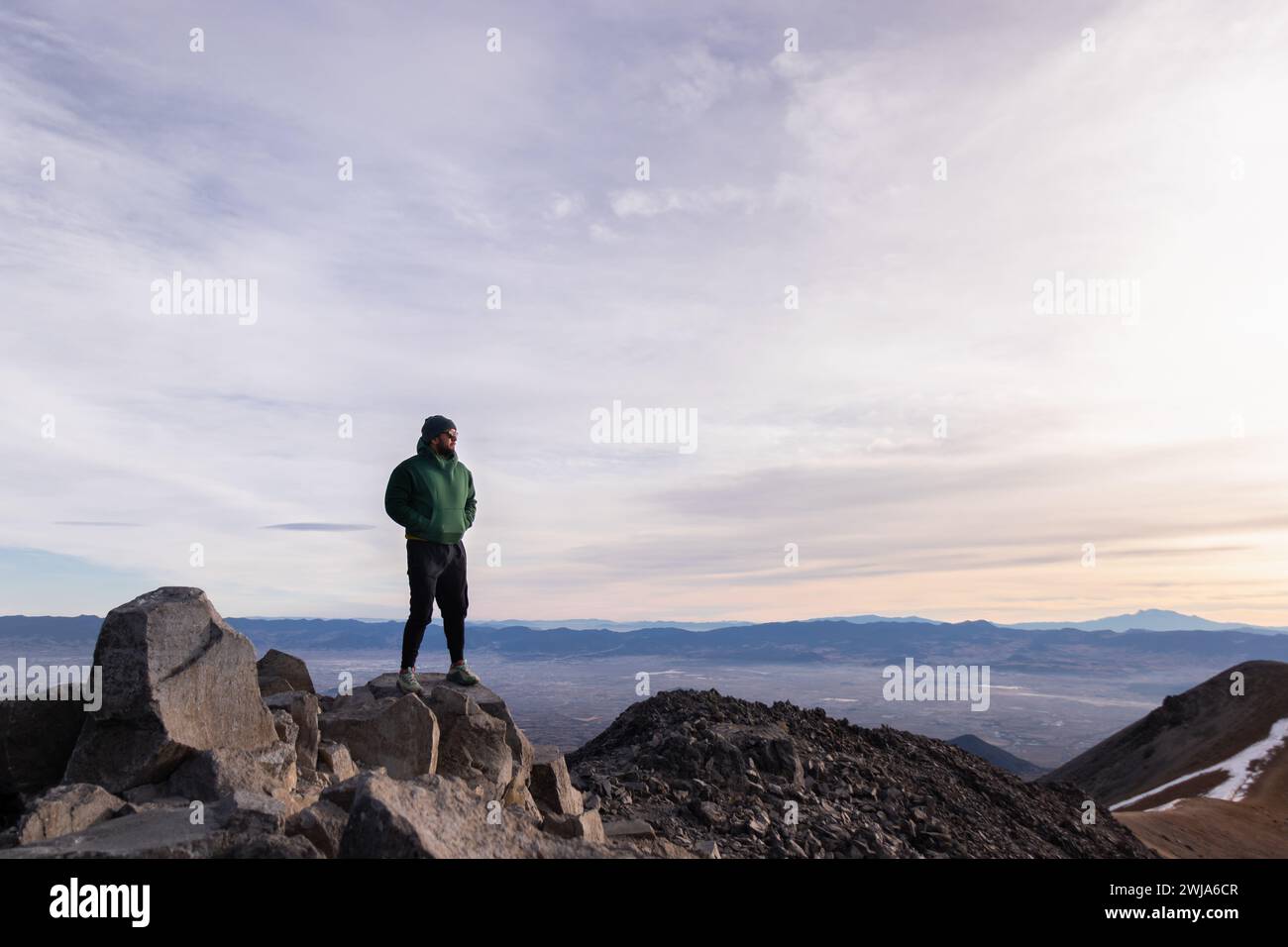 Full body of bearded trekker in activewear standing on edge of rock ...