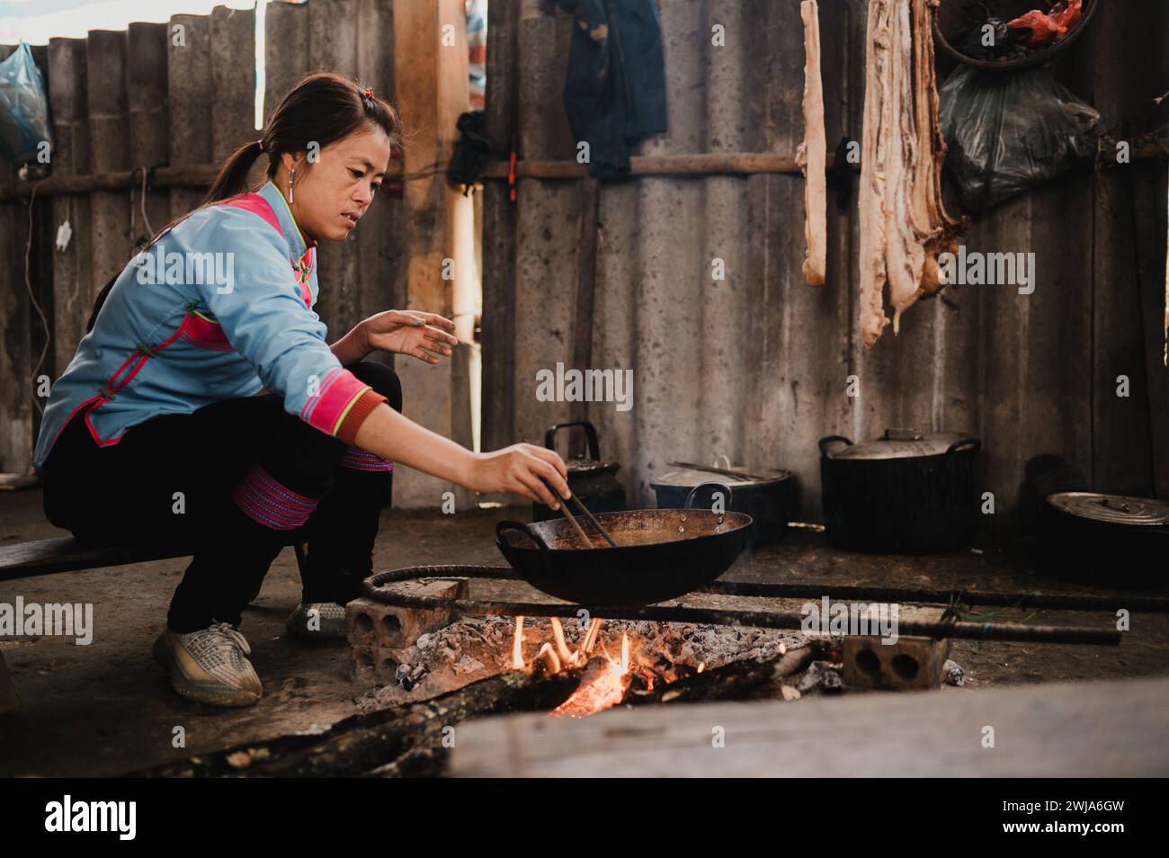 Side view of focused Asian lady sitting on bench and cooking food with ...