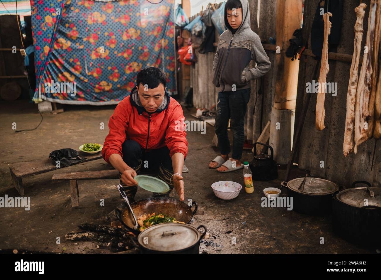 Guy in casual clothes sitting on bench mixing vegetables in the frying ...