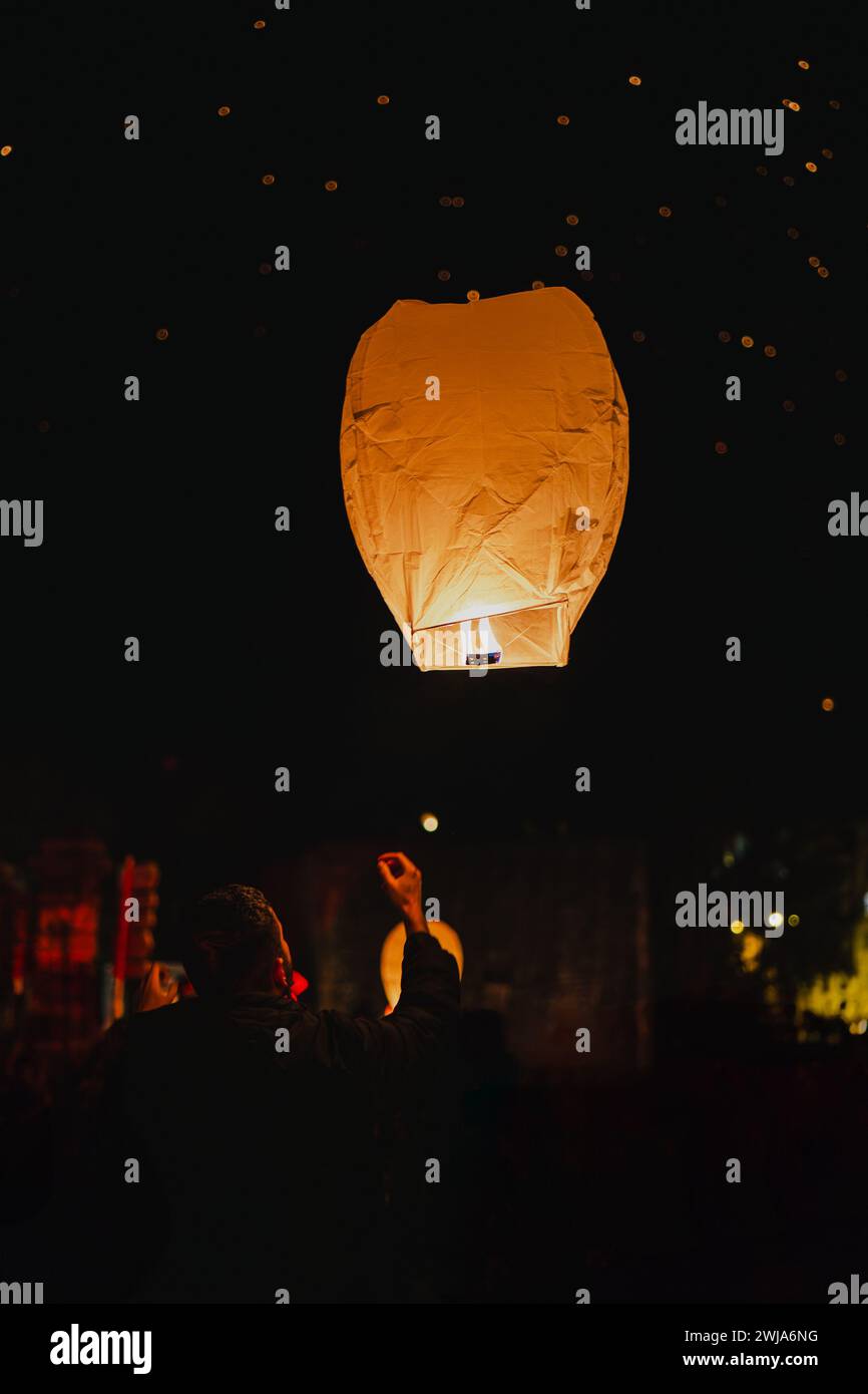 A single glowing sky lantern floats away into the dark night sky ...