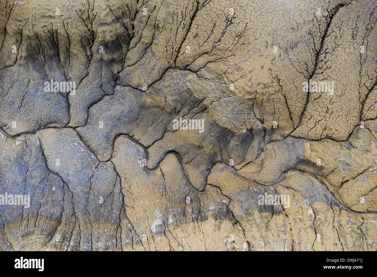 Aerial image of a dried riverbed with deep erosion patterns and cracks ...