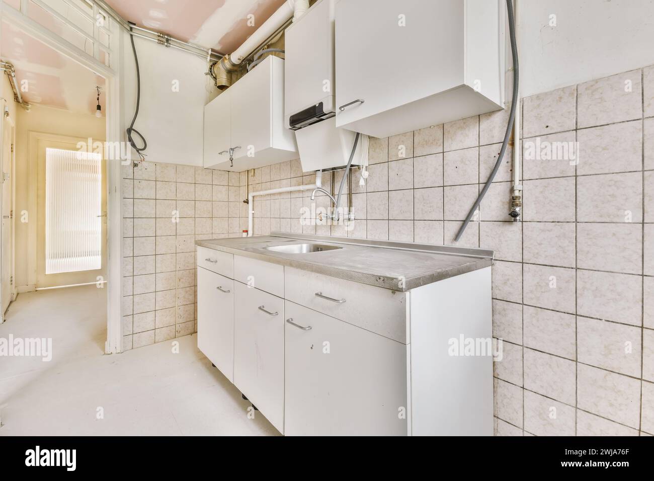 A bright, empty kitchen with unfinished walls, white cabinetry, and ...
