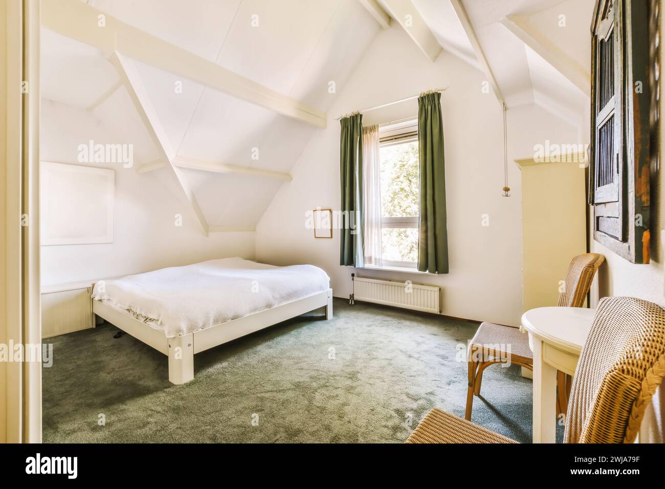 A welcoming attic bedroom featuring a basic bed, white walls, exposed ...