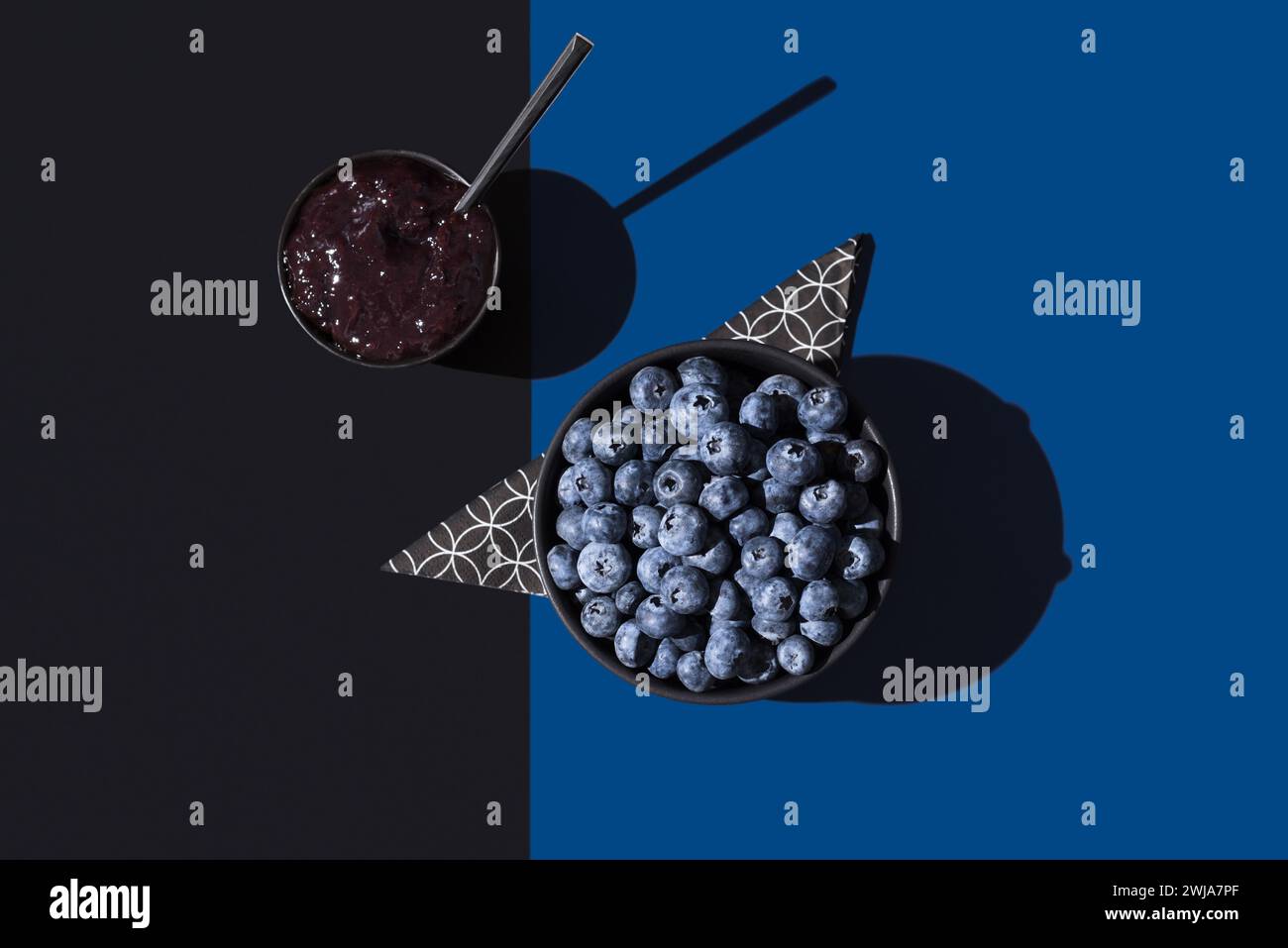 Top view of blueberries in a bowl with blueberry jam on a geometric ...