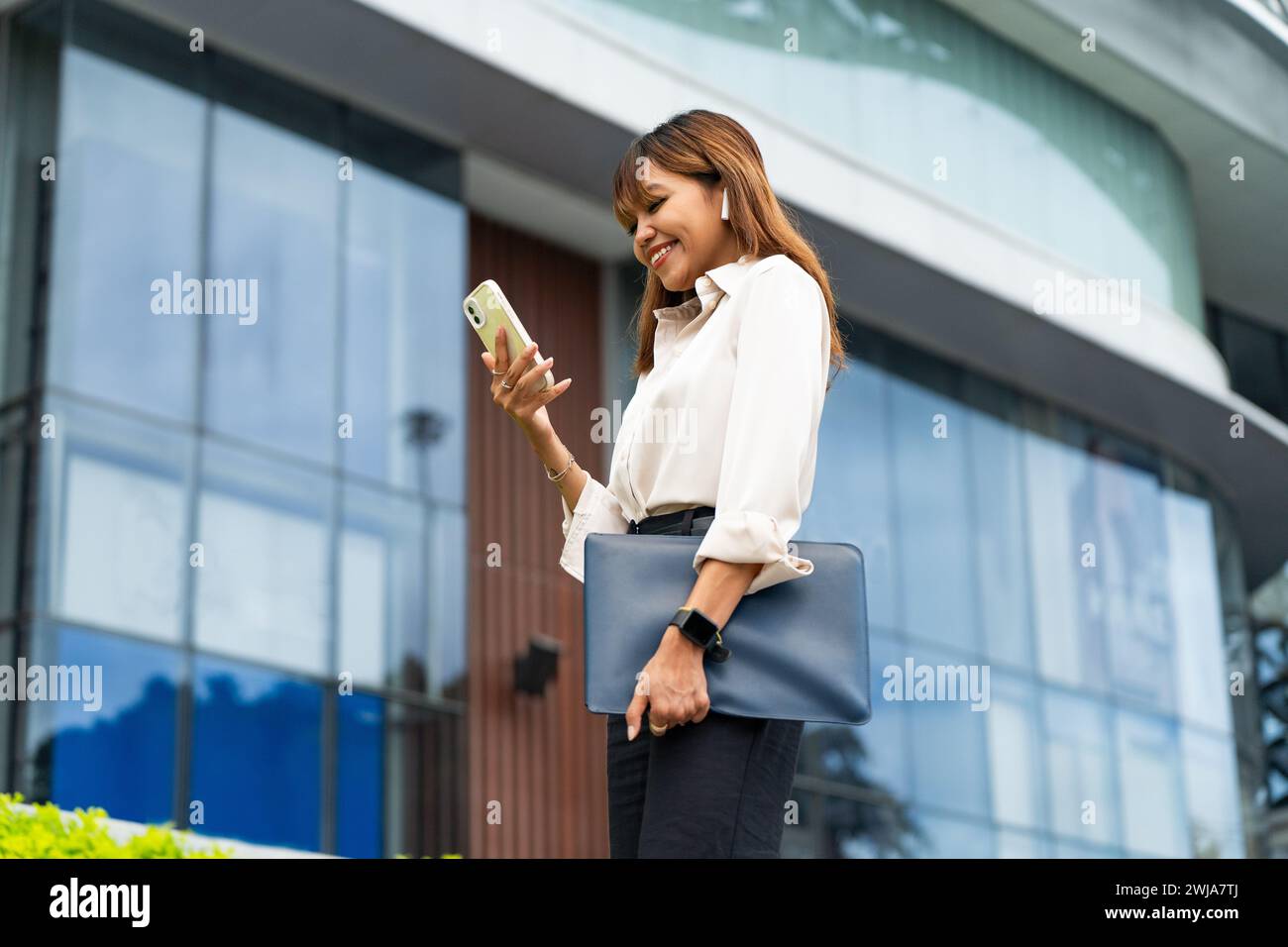 From below Thai Businesswoman checks her smartphone outside a modern ...