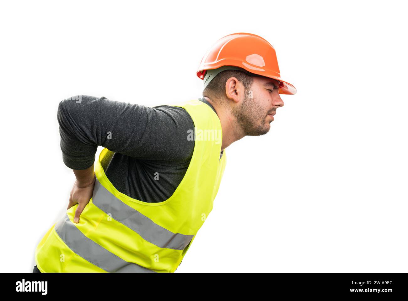 Adult constructor male wearing fluorescent vest and orange safety hardhat touching lumbar area ...