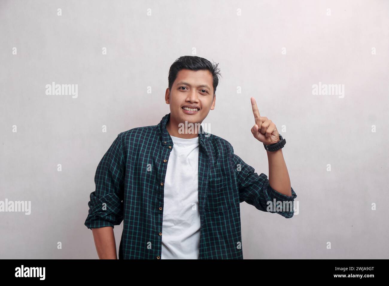 Mature man in plaid dress pointing at camera with one finger up ...