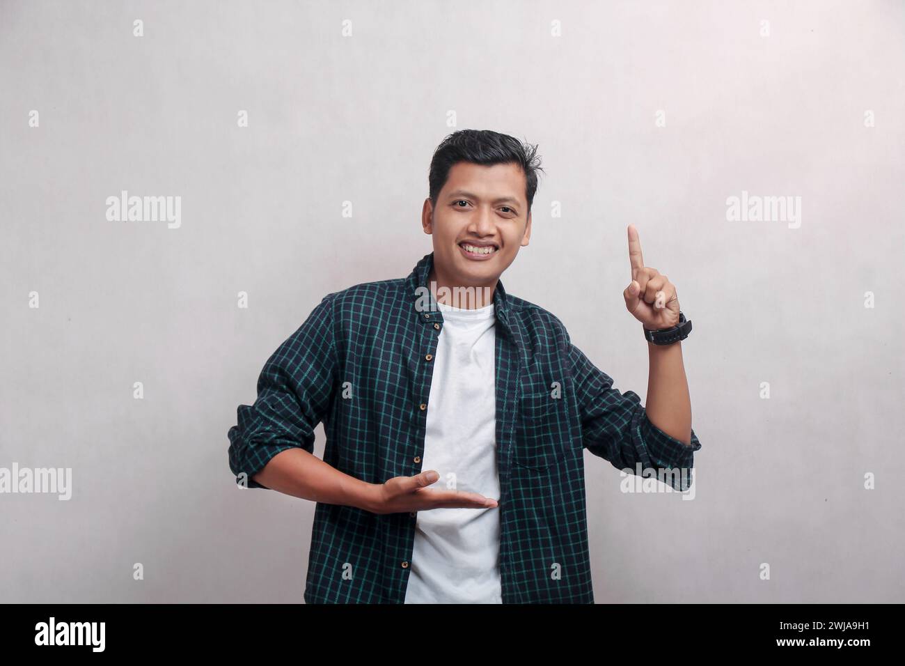Mature man in plaid dress pointing at camera with one finger up and ...