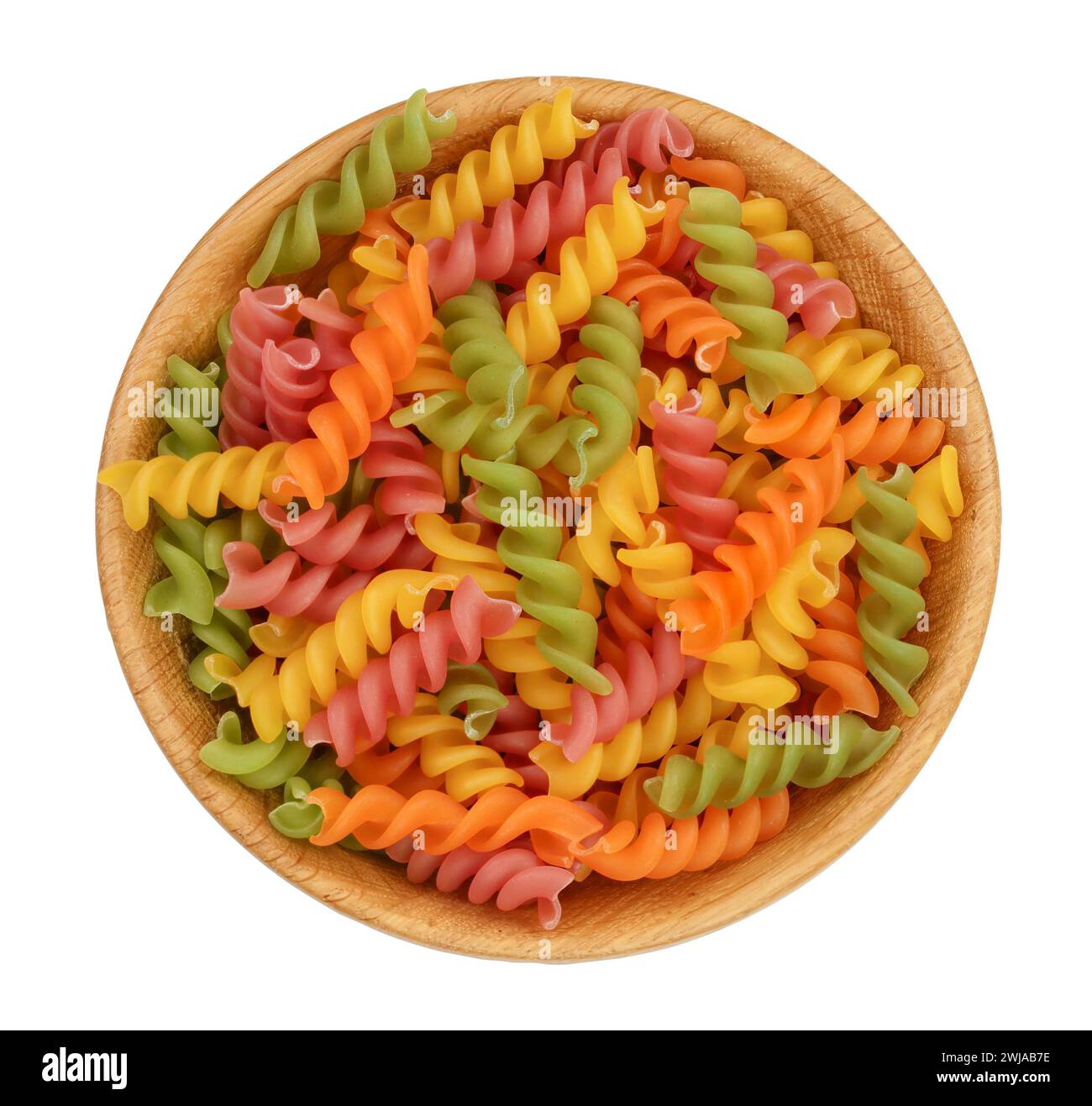 raw Fusilli colored pasta in wooden bowl isolated on white background ...