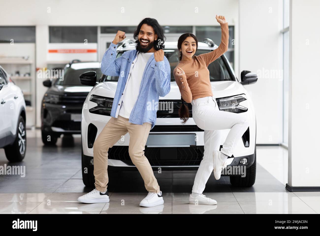 Emotional young couple dancing, jumping and screaming in car saloon ...