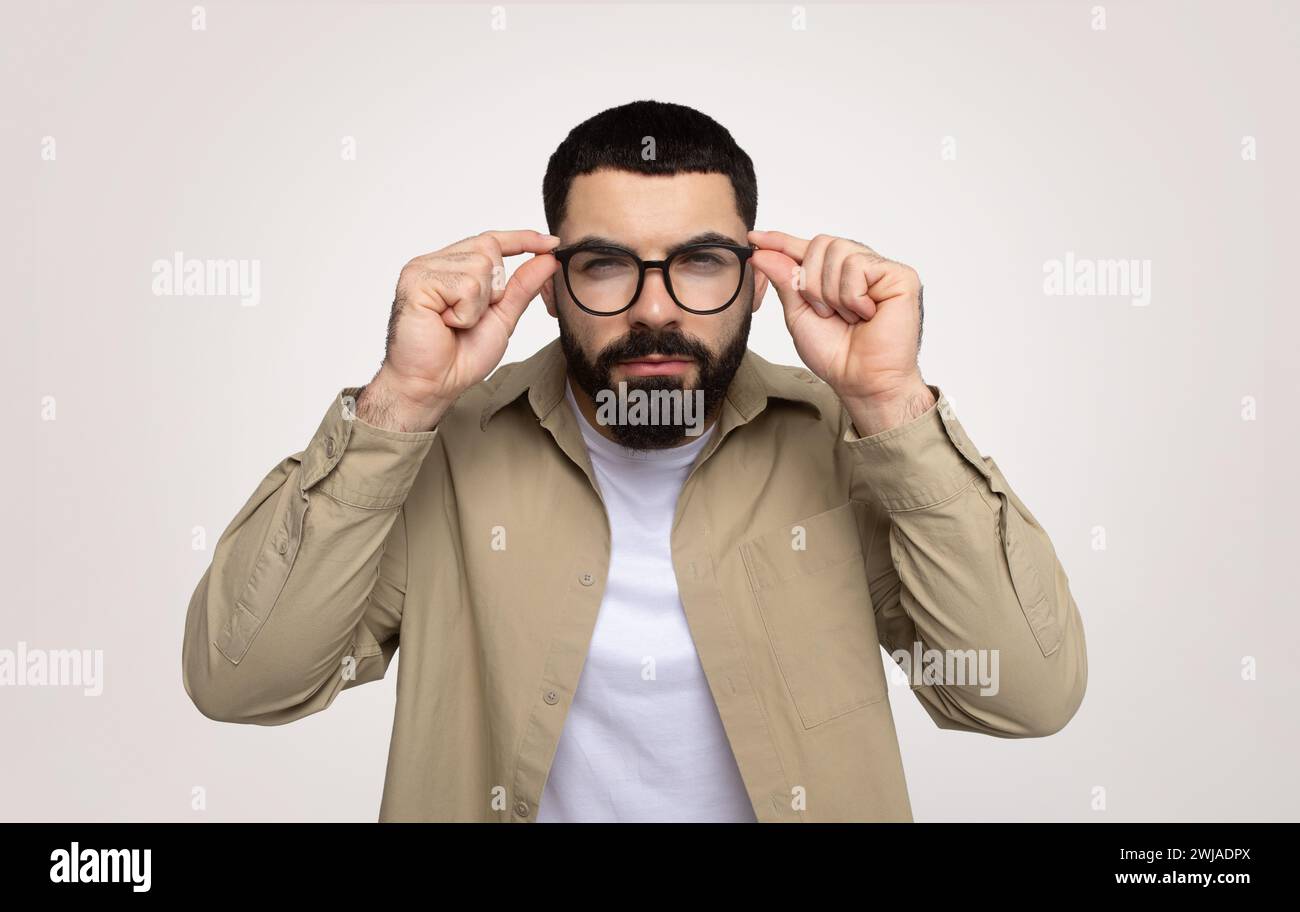 Serious smart millennial middle eastern man adjusting glasses, focused ...