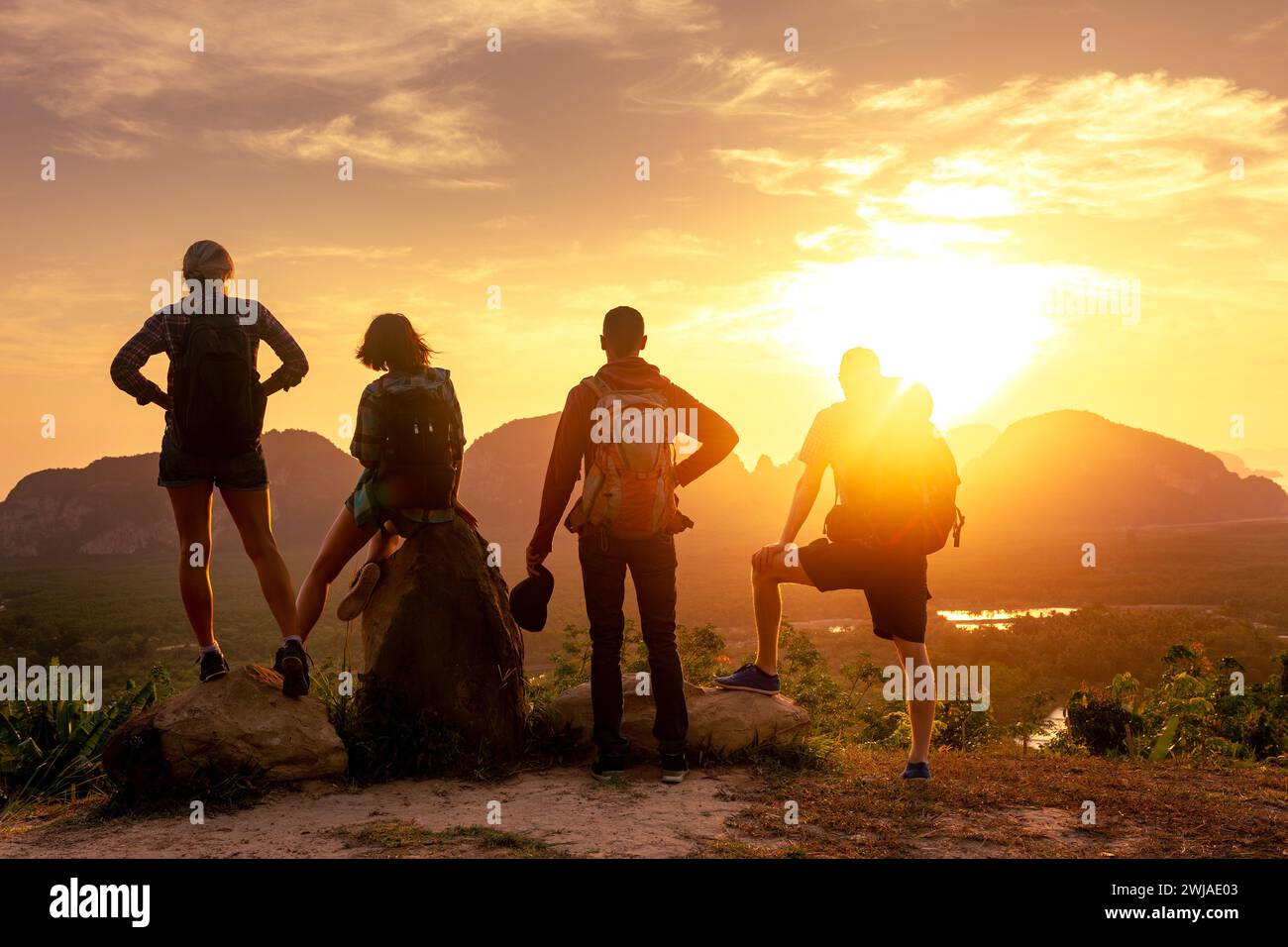 Four young hikers with backpacks and friends are enjoying great view at ...