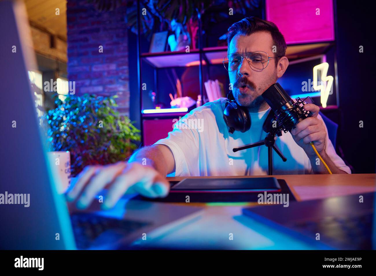 Multitasking podcaster adjusting equipment while speaking into studio ...