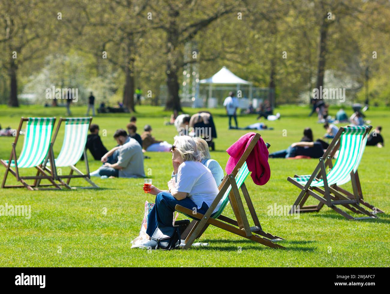People take off their coats and enjoy the sunshine in Green Park ...