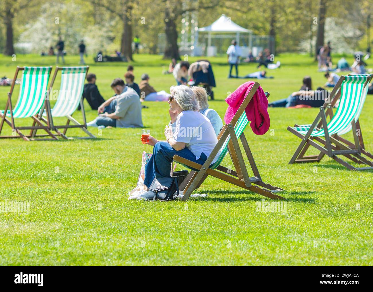 People take off their coats and enjoy the sunshine in Green Park ...