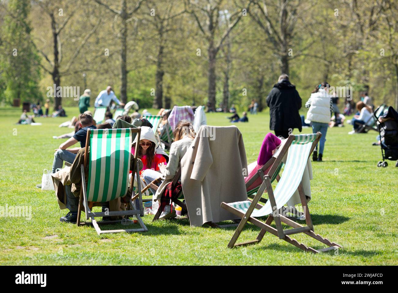People take off their coats and enjoy the sunshine in Green Park ...