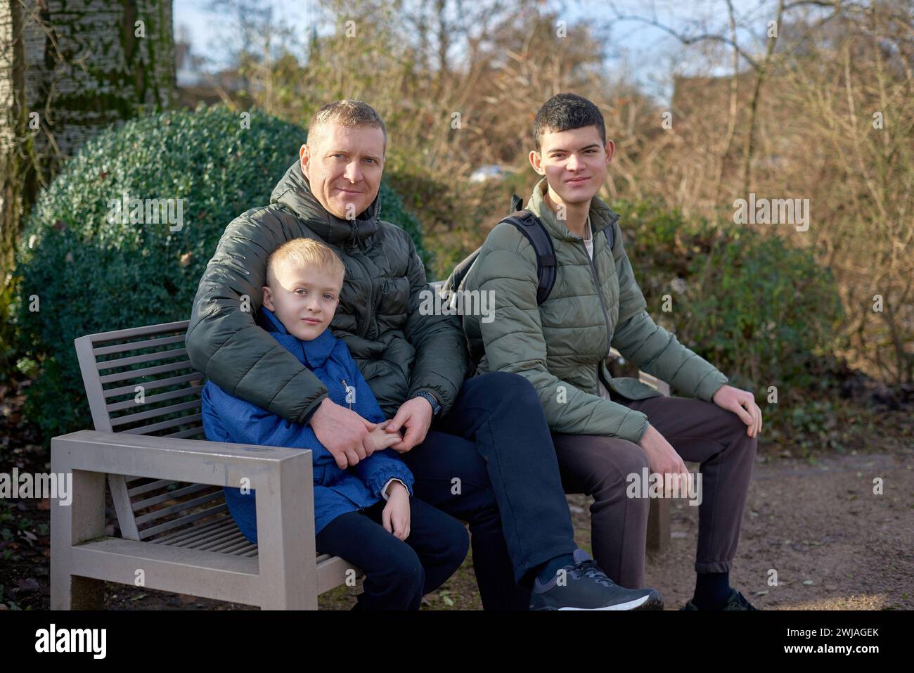 Dad with two sons sitting on a bench in autumn park. Autumnal Family ...