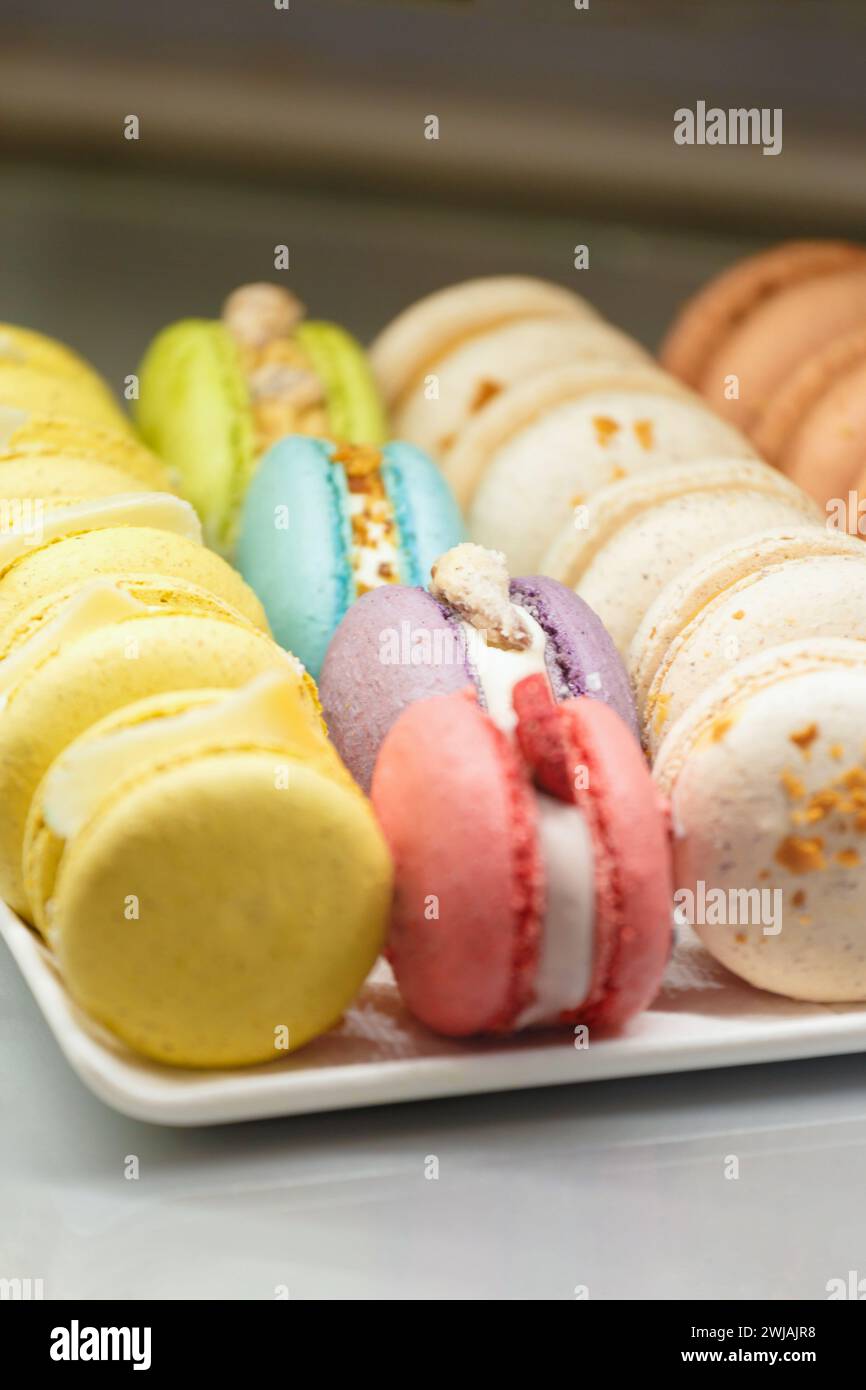 Multi-colored French macaroon cakes on display in a pastry shop, coffee ...