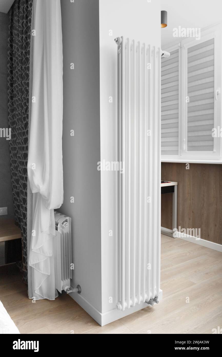 Modern designer vertical white heating radiator mounted on the wall in ...