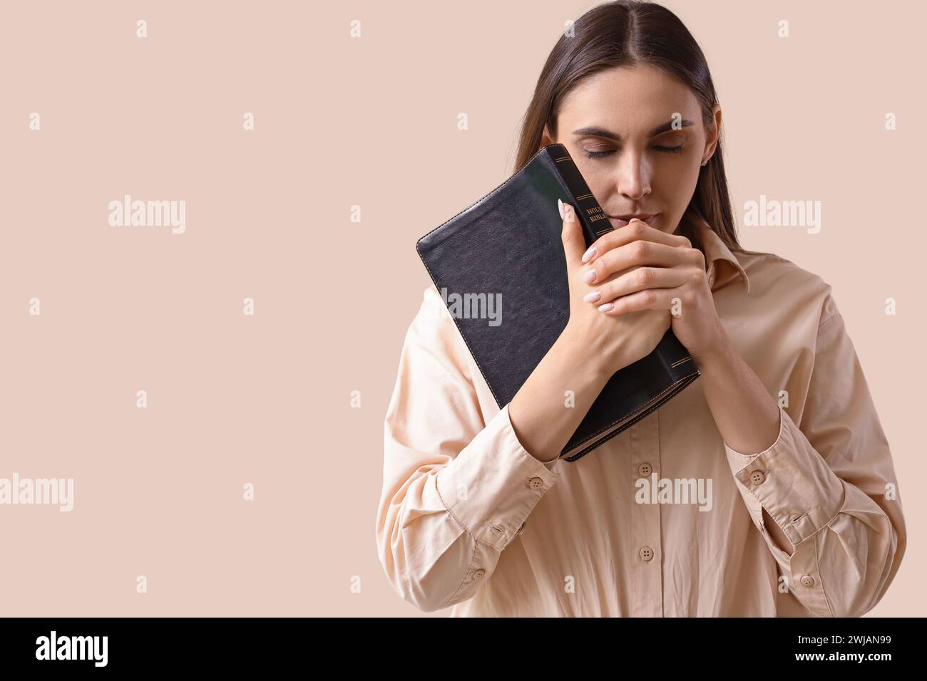 Beautiful woman with Holy Bible praying on light background Stock Photo ...