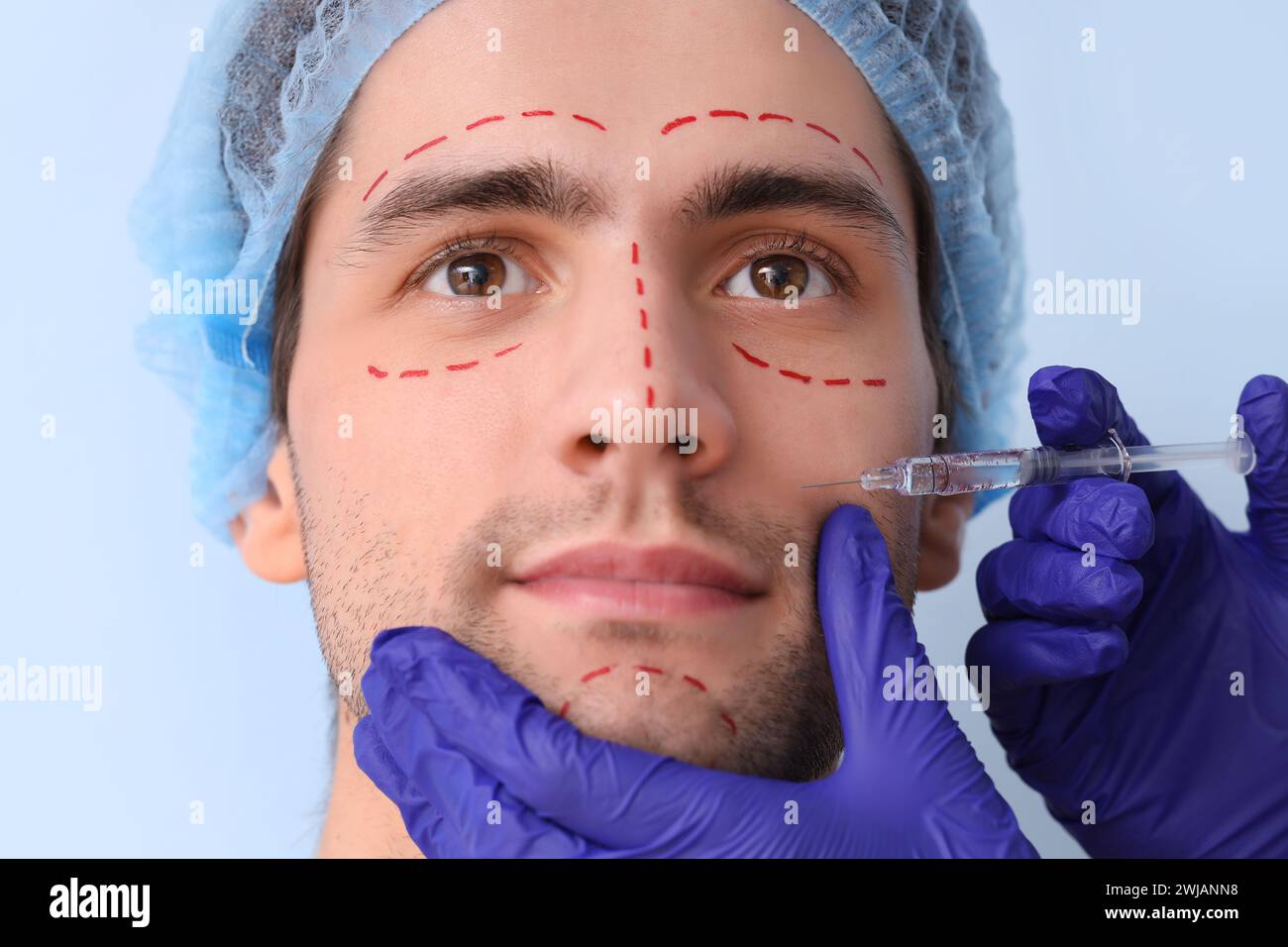 Young man with marked face receiving injection on blue background ...