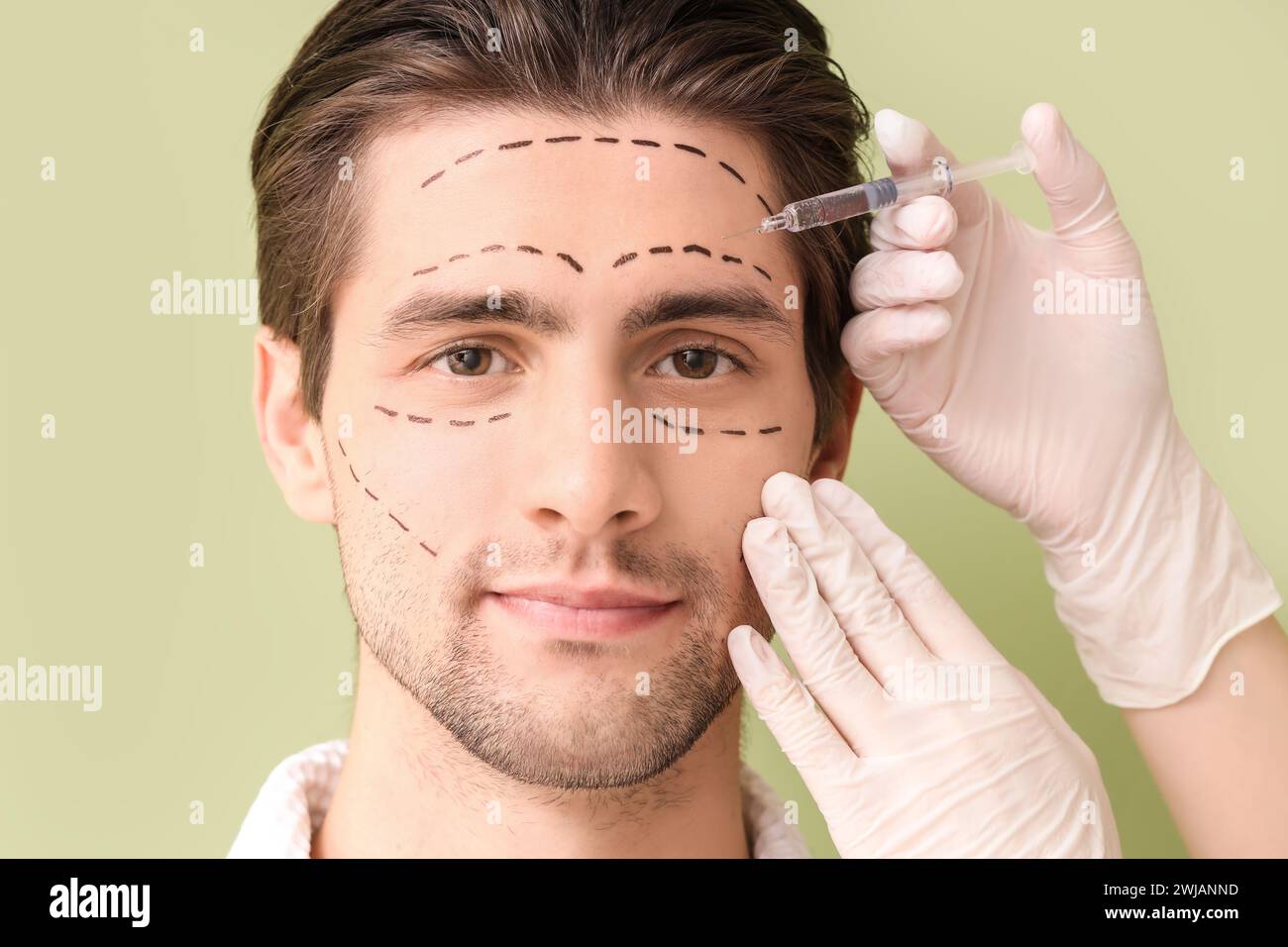 Young man with marked face receiving injection on green background ...