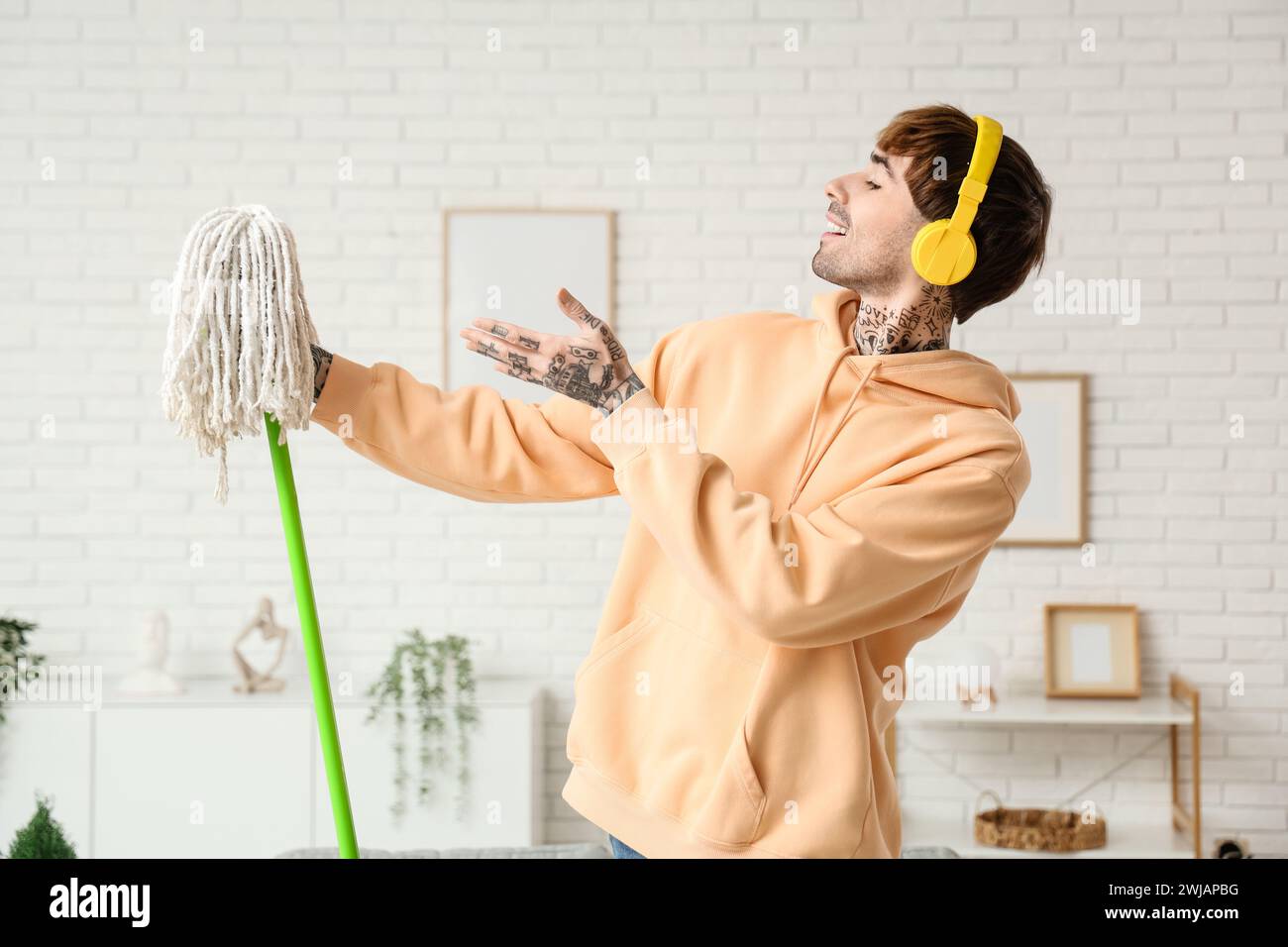 Young tattooed man dancing with mop while cleaning his flat Stock Photo ...