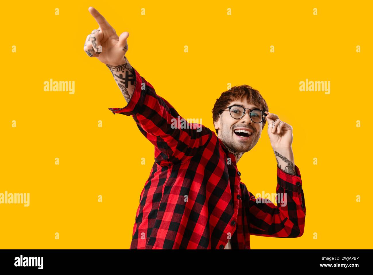 Young tattooed man dancing against yellow background Stock Photo - Alamy