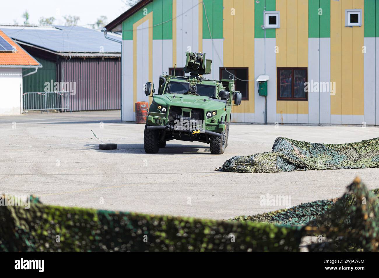 A green armored and camouflaged military vehicle driving at a show ...