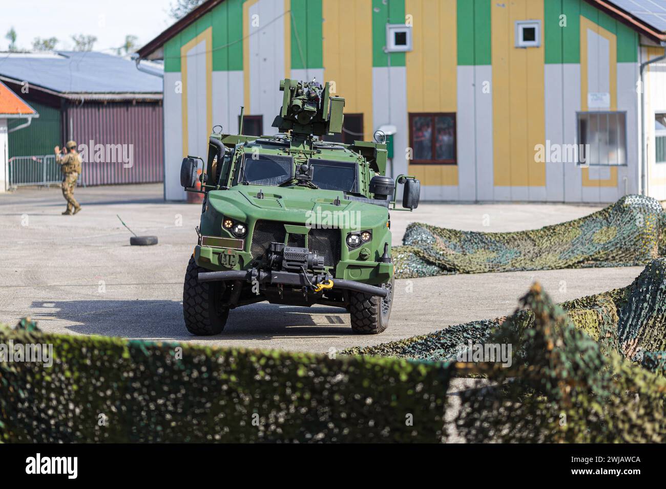 A green armored and camouflaged military vehicle driving at a show ...