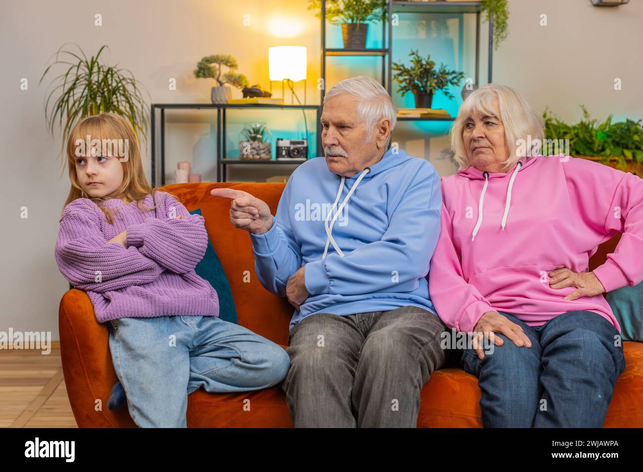 Irritated grandfather and grandmother scolding granddaughter for bad ...